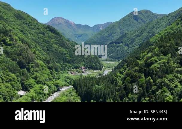 Lush green mountains surrounding winding river valley Stock Video ...