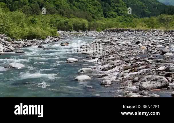 Clear river flowing through rocky landscape surrounded by greenery ...