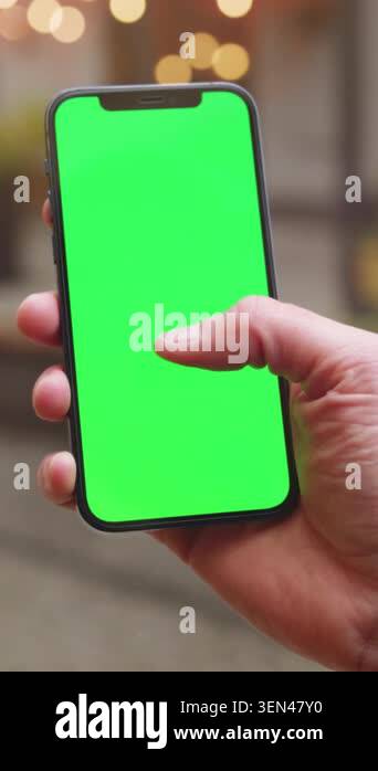Green screen smartphone held by hand against blurred bokeh lights ...