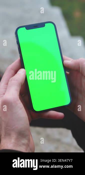 two hands holding phone on concrete steps with green screen, calm ...
