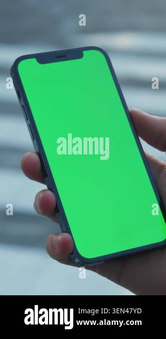 hand holding smartphone green screen on urban crosswalk, quick thumb ...