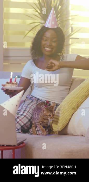 black woman celebrating birthday at home wearing party hat and holding ...