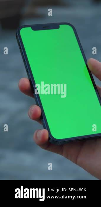 hand holding smartphone green screen near waterfront, closeup grip and ...