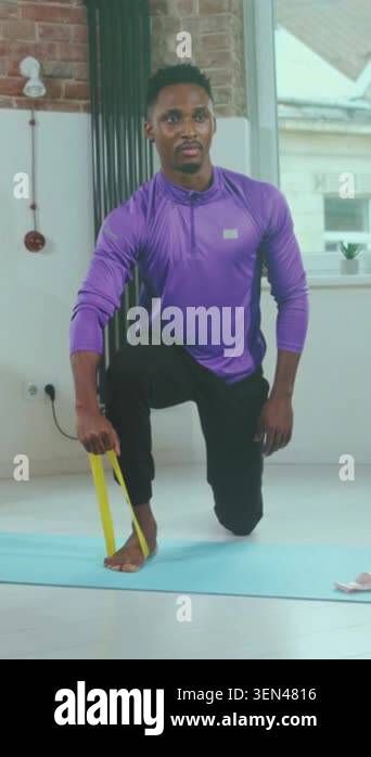 black man kneeling with resistance band, focused trainer demonstrating ...