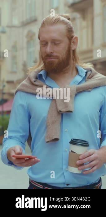 white man city street holding coffee, checking smartphone while ...