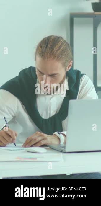 caucasian man writing beside laptop, focused on sketches and notes, pen ...