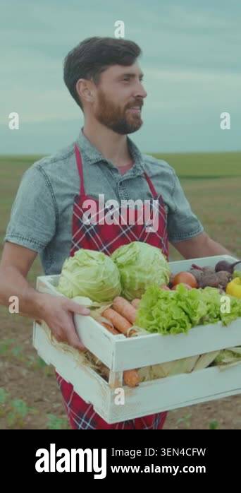 man holding overflowing crate of produce at chest level, bright red ...