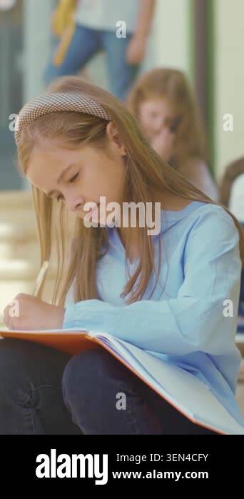 Young white girl studying on steps with notebook and pen, blue sweater ...