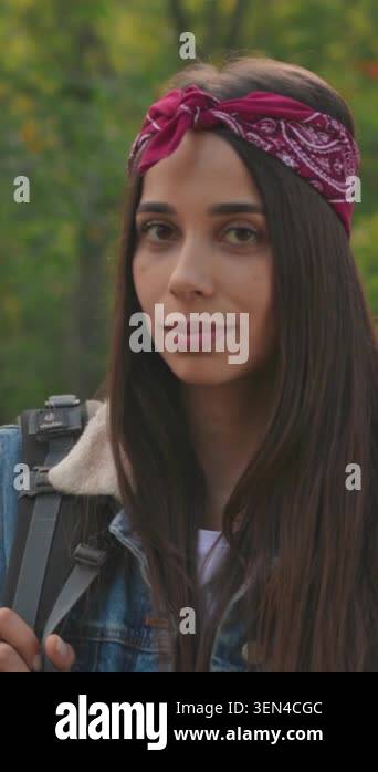 young woman with bandana outdoors, denim jacket and backpack, closeup ...