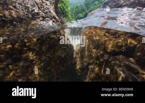 Half underwater view of crystal clear stream flowing over granite rocks ...