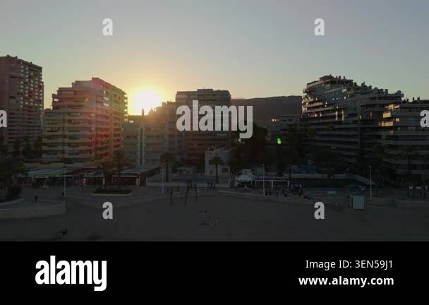Calpe beachfront apartment buildings at sunrise with golden sun between ...