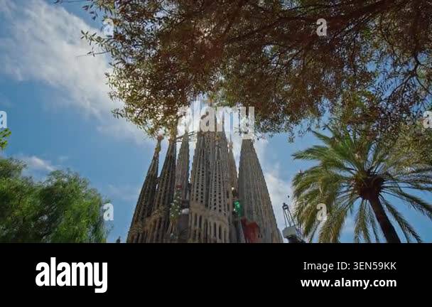 Sunburst through tree canopy framing Sagrada Familia basilica in ...