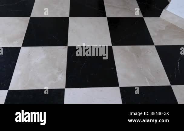 Slow pan across black and white checkered marble tile floor in an empty ...