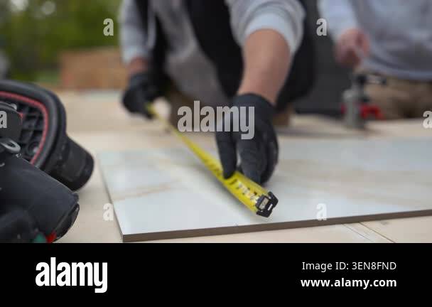 Labor measuring and marking large ceramic tile before cutting ...