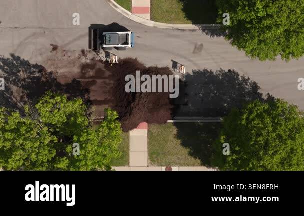 Aerial top down shoot of Skid steer loader transporting fresh mulch ...