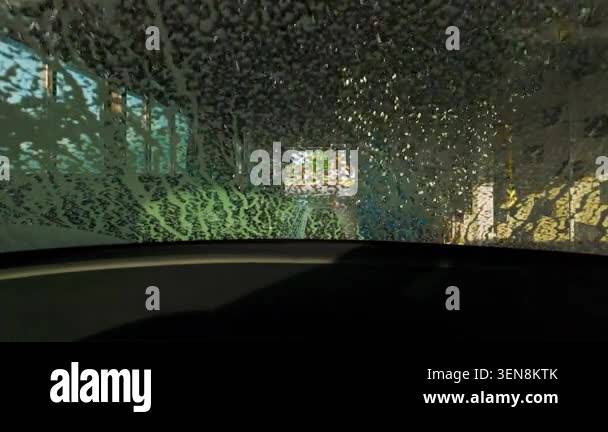 Wide POV footage from the inside of car in automatic car wash system ...