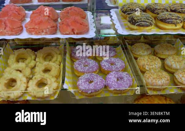 Colorful assortment of fresh donuts displayed inside a bakery showcase ...