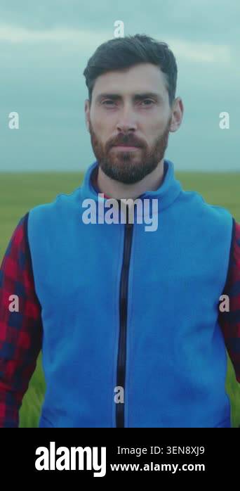 Caucasian farmer standing in open field, wearing blue fleece vest and ...