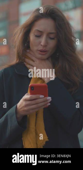 caucasian woman coughing while checking phone near city street in ...