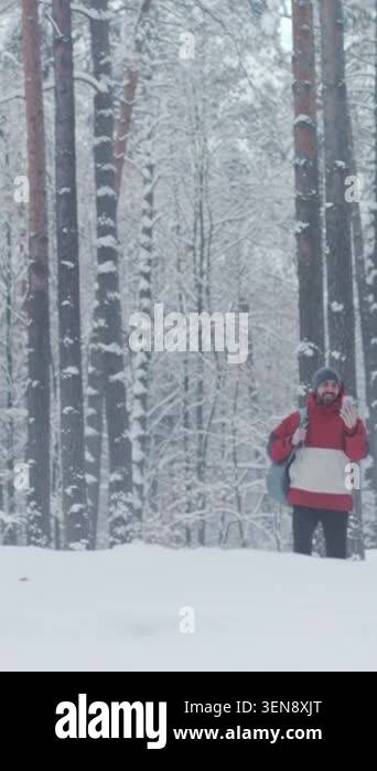 caucasian man with red jacket waves phone while streaming through snowy ...