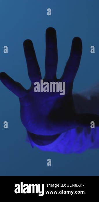 Reaching hand under deep blue light toward locked biometric interface ...