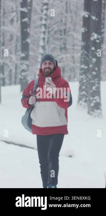 caucasian man walking on snowy trail checks phone for route, brisk ...