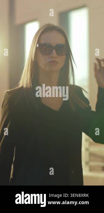 white woman adjusting sunglasses confidently on sunlit city steps ...