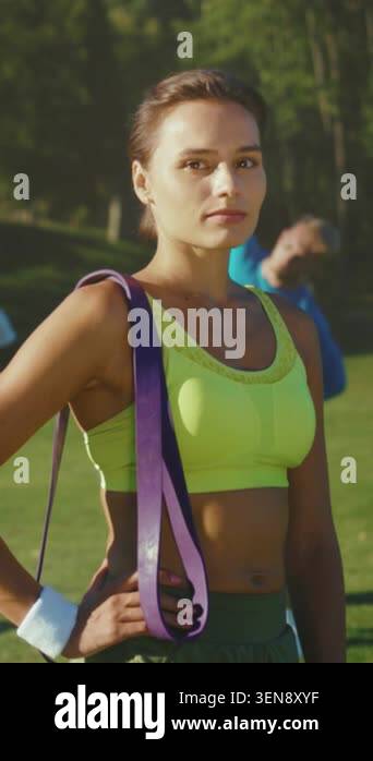 Young woman athlete in park wearing neon sports bra and carrying purple ...