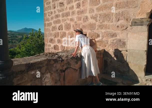 A happy woman explores an old medieval Spanish village, taking in the ...