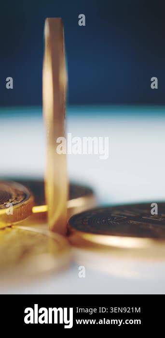 A man holds a shiny bitcoin coin while surrounded by other coins in a ...