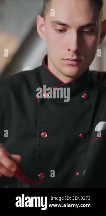 Man shapes pizza dough and adds toppings in a busy kitchen at night ...