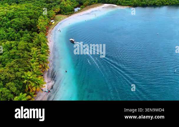 Aerial of Curved Caribbean Beach with Passenger Boat Wake. A passenger ...