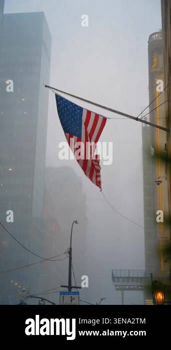 American flag hanging on the pole on the building facade. Heavy ...