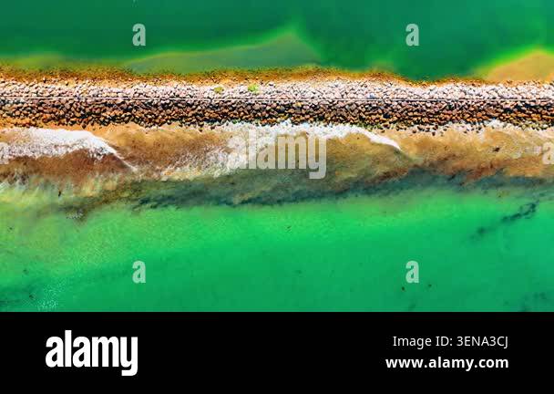 Beautiful clear sea-green water along the dam. Waves hot the stone ...