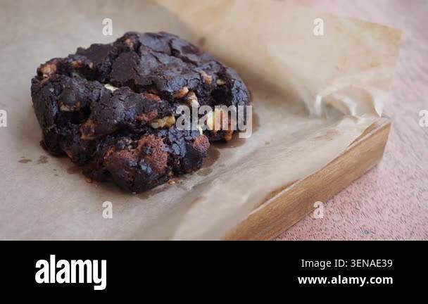 A chocolate cookie is placed on a wooden plate with parchment paper ...