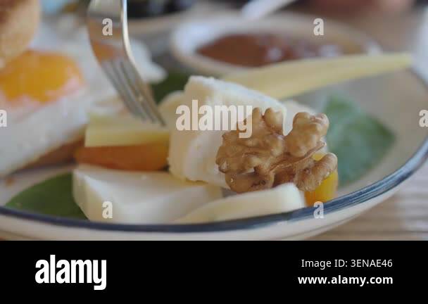 A person enjoys a breakfast plate with eggs, cheese, nuts, and fruit ...