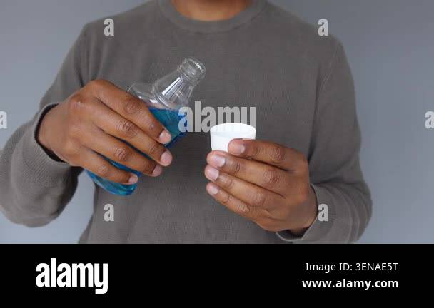 Person pours mouth wash liquid in a bottle cap Stock Video Footage - Alamy