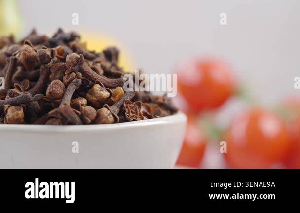 Cloves are shown in a bowl with red tomatoes behind them Stock Video ...