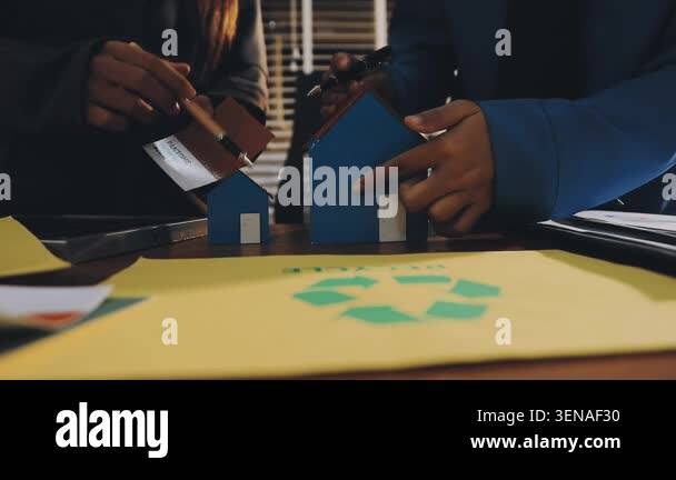 close up of man holding paper with house model and green house model ...