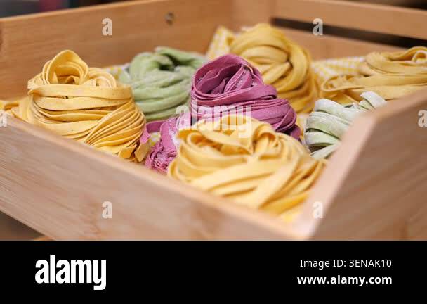 A close look at freshly made, colorful pasta in a wooden box Stock ...