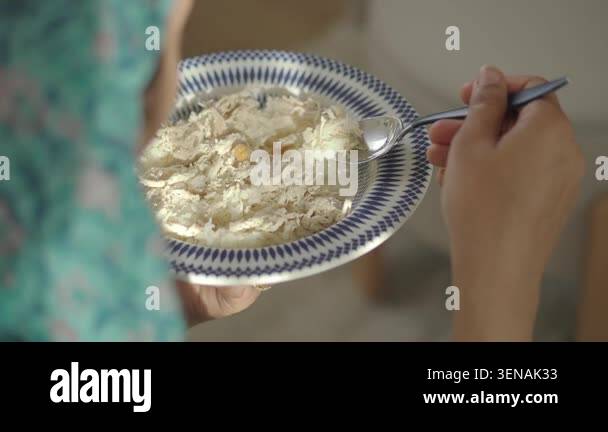 Person eats a plate of shredded chicken with rice using a spoon Stock ...