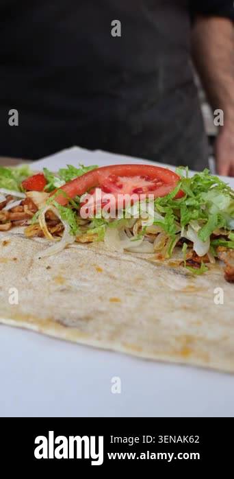 chicken wrap being assembled, featuring fresh tomatoes and shredded ...