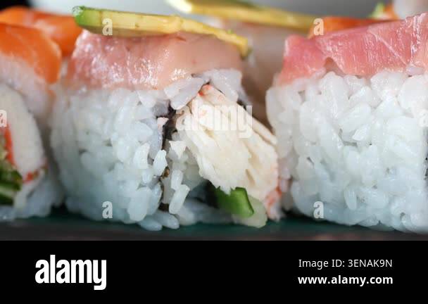 Chefs prepare sushi with fish and rice in a kitchen setting at noon ...