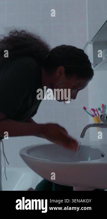 Young African American Woman washing cleanser from face in modern ...