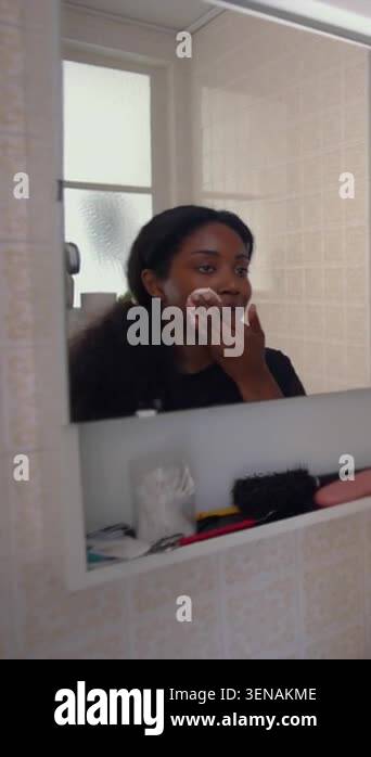 Young African American Woman completing personal skincare routine while ...