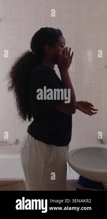 Young African American Woman spreading moisturizer onto face while ...