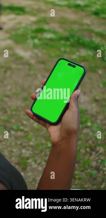 Young African American Woman displaying blank smartphone screen in park ...