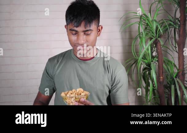 A boy sits indoors looking at a bowl of cashews in his hands Stock ...