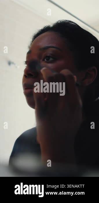 Young African American Woman using cosmetic brush on cheek in modern ...