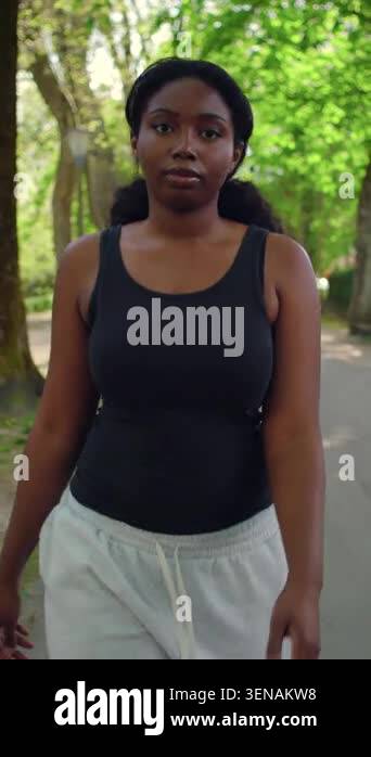 Young African American Woman moving through green park environment with ...